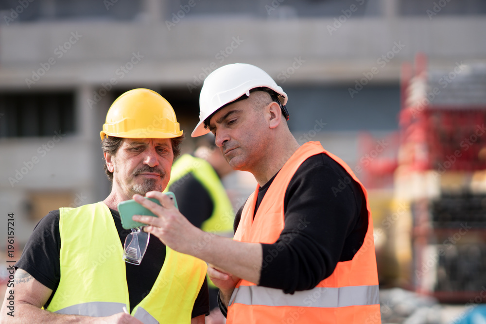Construction workers at work on construction site using an electronic ...