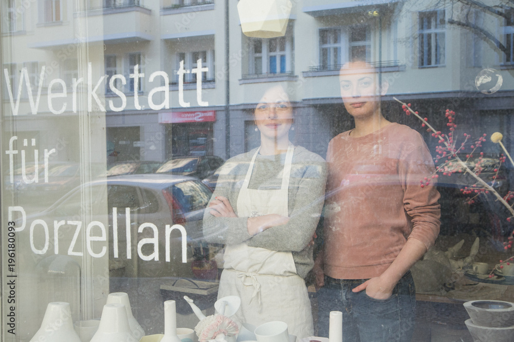 Two ceramic artists seen through the window of a pottery workshop ...