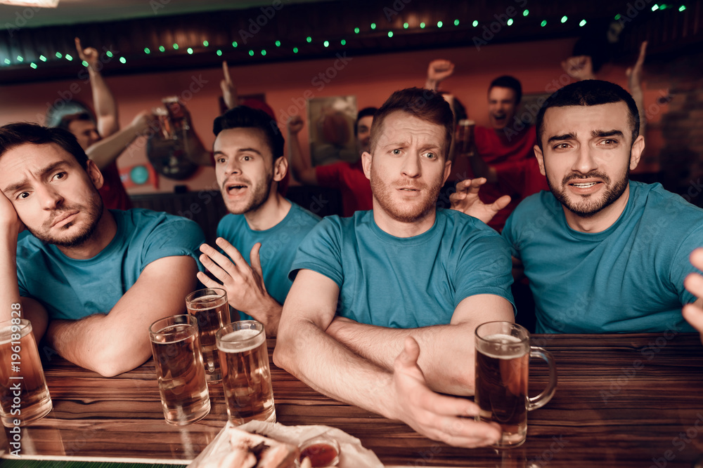 Sad blue team fans at bar in sports bar with red team fans cheering in ...