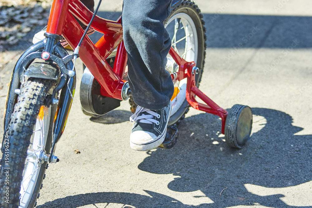 Little child boy cycling on bicycle in green park outdoor in spring. A ...