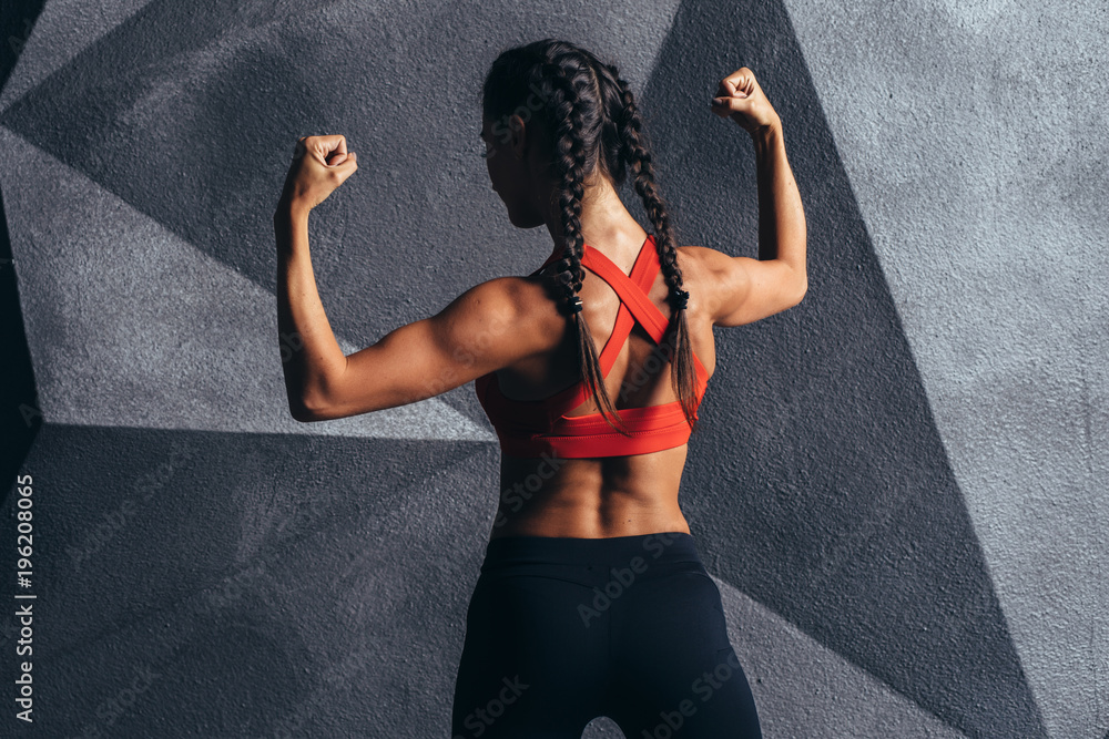 Fitness model posing showing muscles of the back and biceps. Stock ...