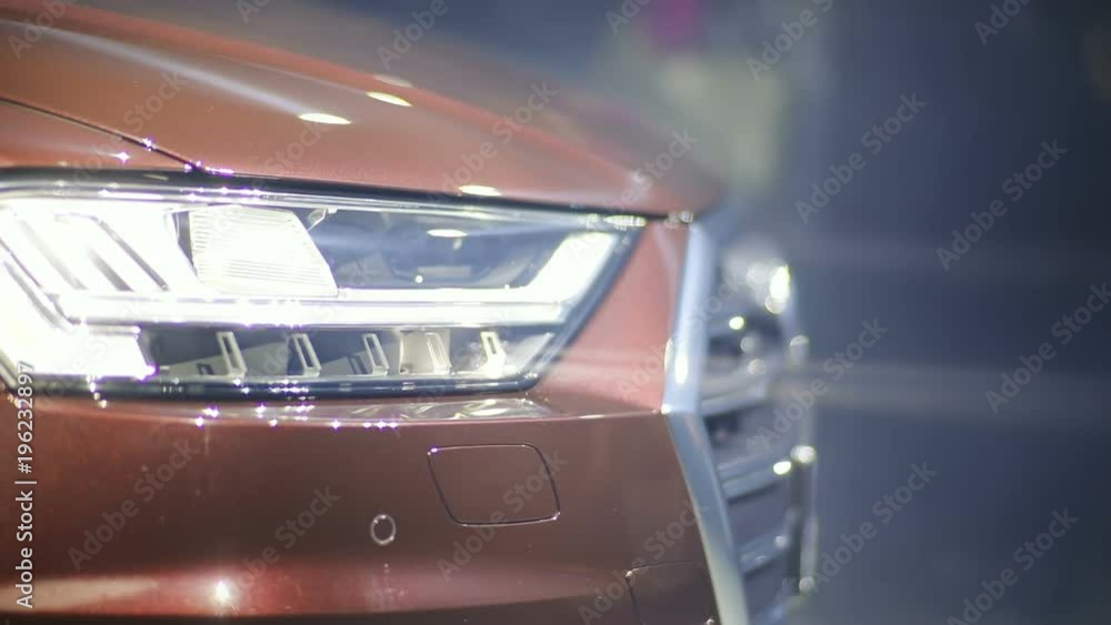 closeup side view of a working headlight of a new luxury car ...