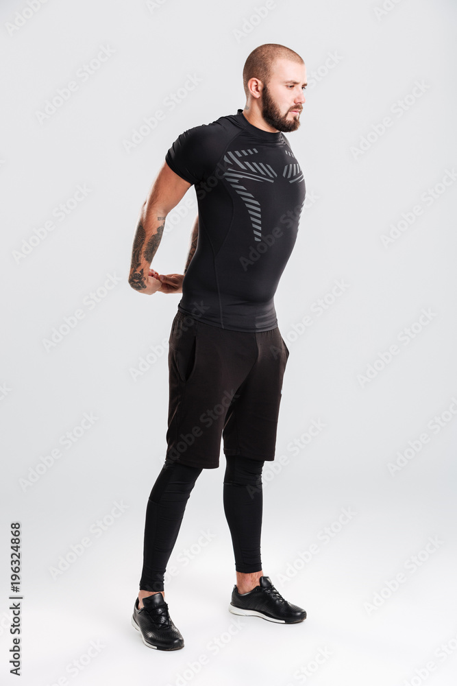 Full-length portrait of strong-willed tattooed man in black sportswear ...