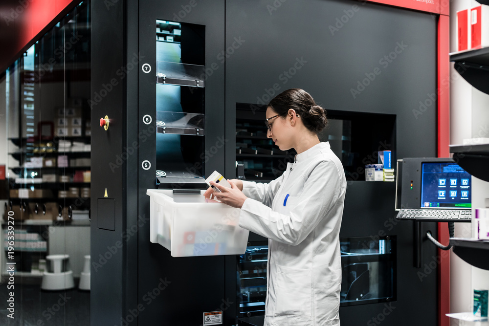 Pharmacist using a computer while managing the drug stock Stock Photo ...