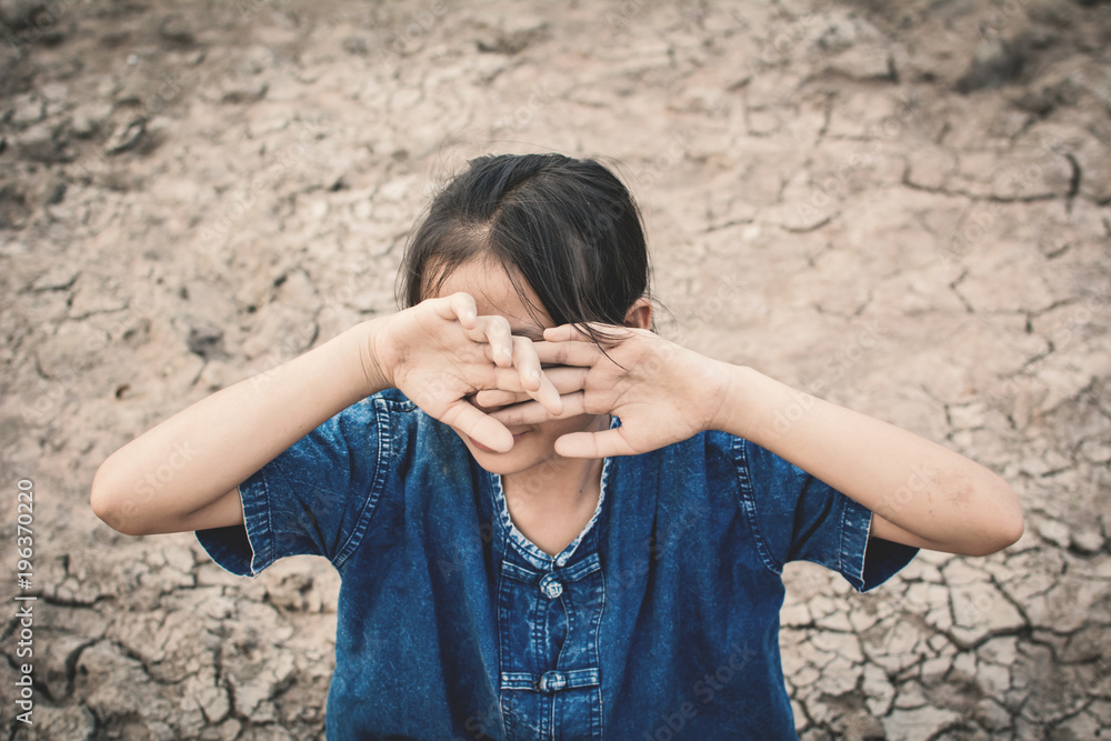 Sad girl praying for the rain on cracked dry ground , Concept drought ...