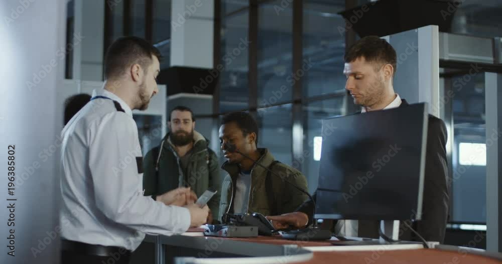 Security officer checking a male passenger thumb print and passport at ...