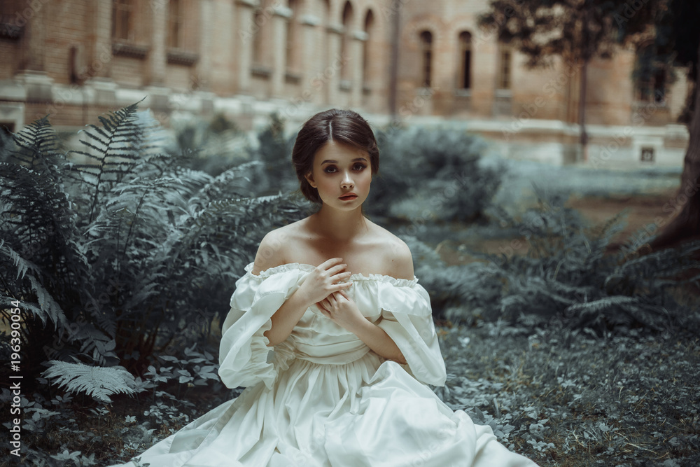 An incredibly beautiful princess sits in the castle garden amid the ...