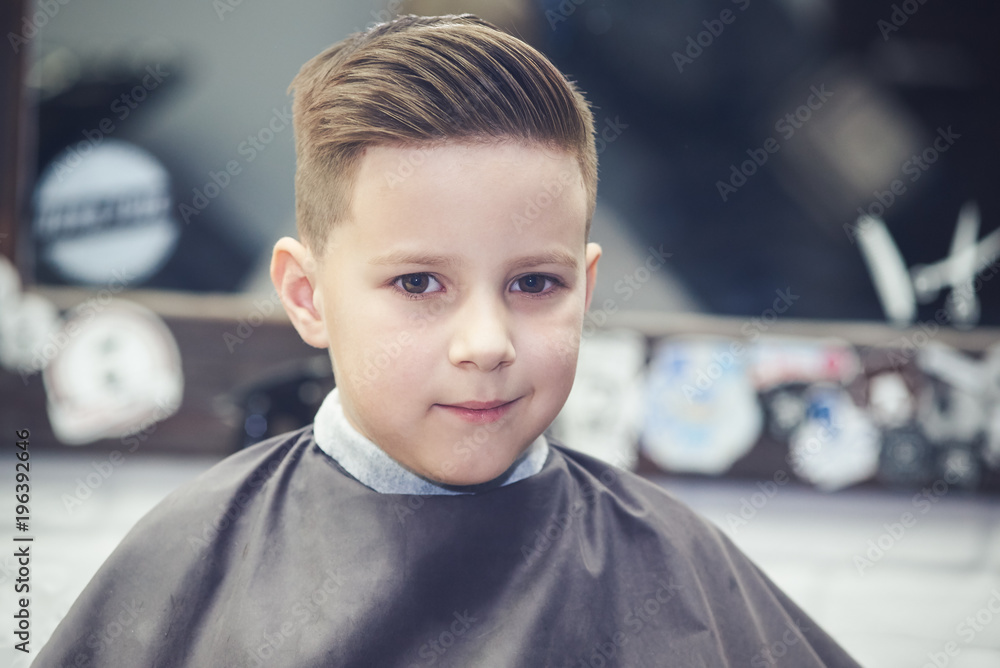 Barber shop. Boy with a totally new look is looking to a camera. foto ...