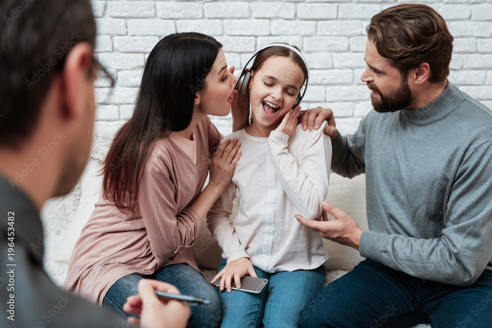 Upset parents try to reach out to little girl in headphones. Deficiency ...