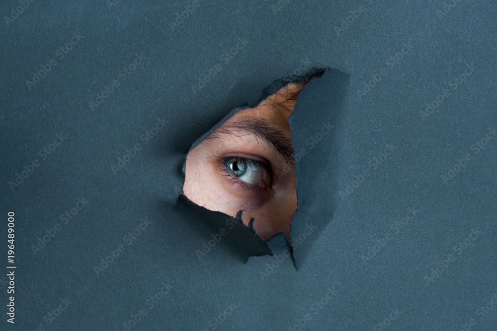 Eye looking through paper. Spy eye watching through a hole. Eye looking ...