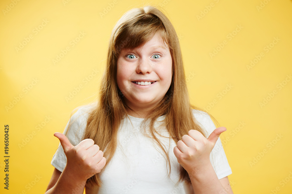 chubby redhead teen girl showing thumbs up standing on a yellow ...