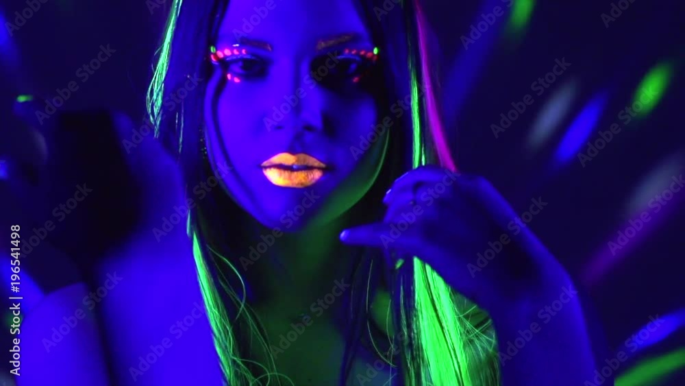 Fashion model girl with colorful fluorescent makeup in ultraviolet neon ...