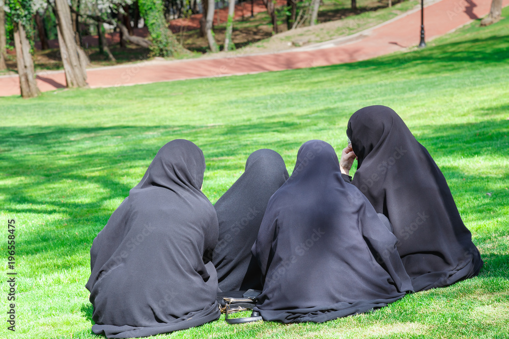 Four Muslim women in traditional clothes hijab sitting on the ground on ...