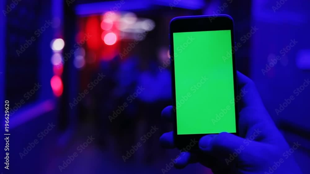 Man's hand using mobile smartphone with blank green screen in the ...