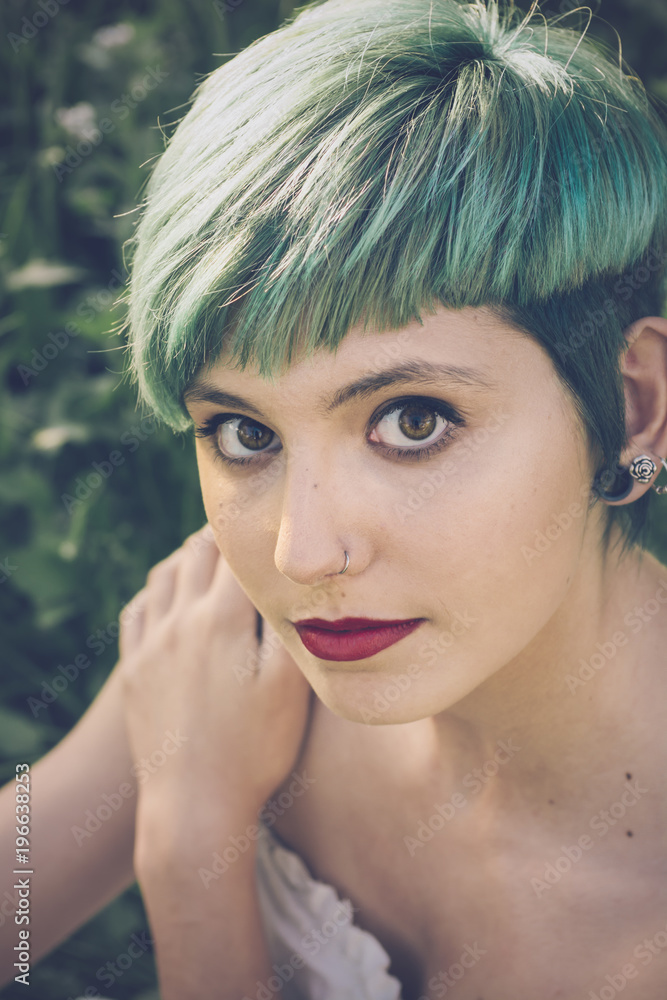 Portrait of a young, beautiful woman with green short hair in nature ...