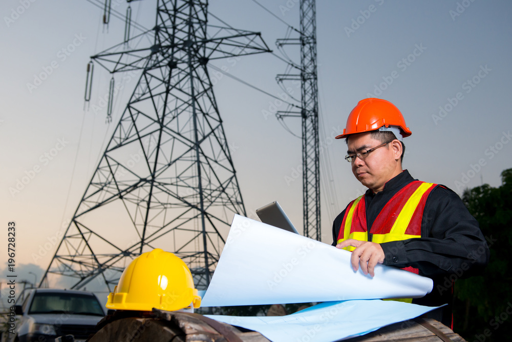 Electrical engineer working. Electrician holding blueprint and looks ...