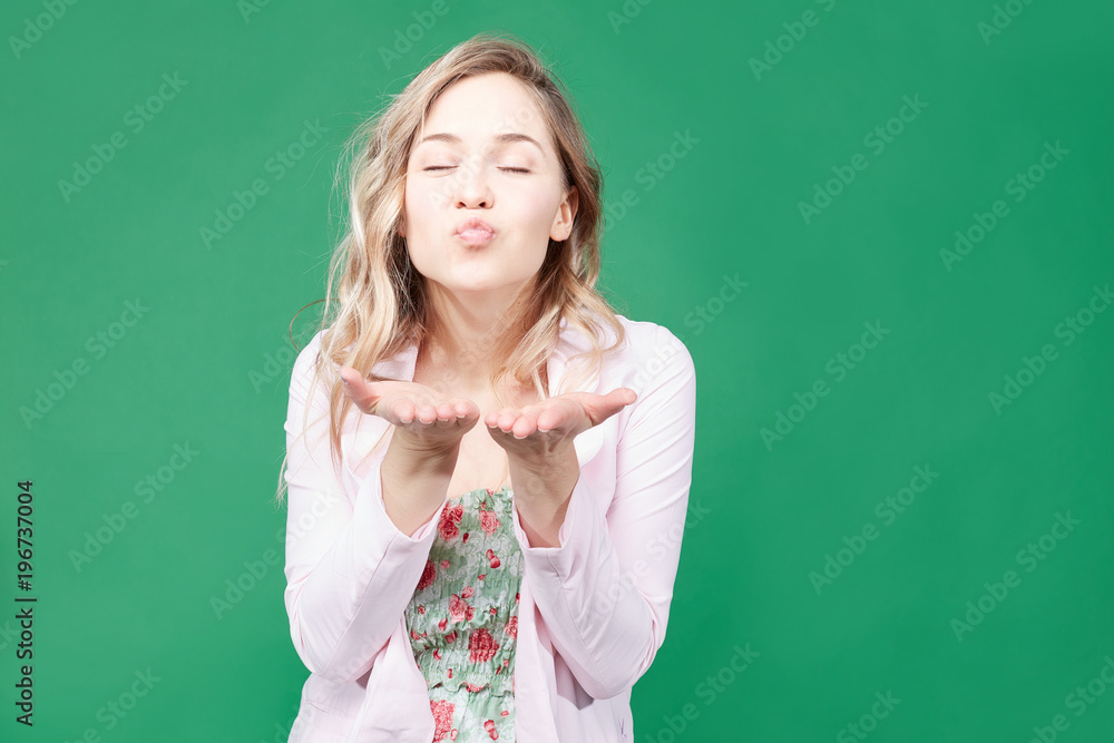 Pleasant looking Caucasian blonde female blows kiss at camera, rounds ...