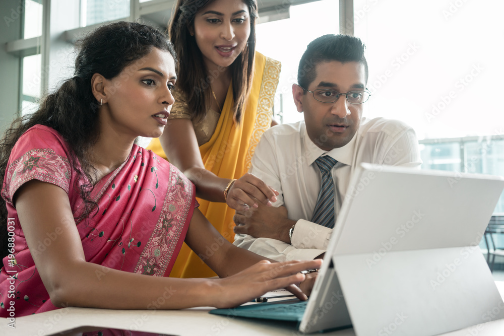 Three creative Indian employees working together around a laptop in a ...