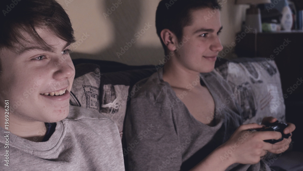 Two friends (guys) play video game console, have fun, laugh, hold the ...