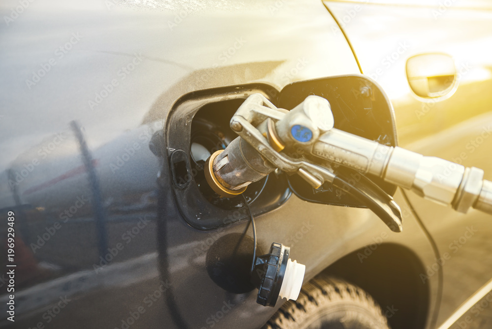 car fuel up with gas. close up refueling gun in the neck of the tank ...