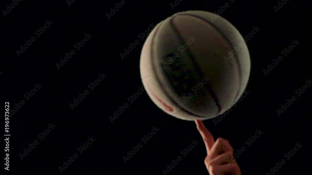 spinning a basketball in front of a black studio background in ...