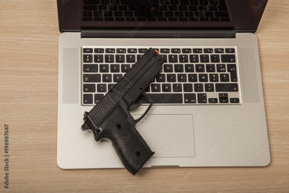 Conceptual photo, weapon on a laptop as a symbol of organized crime ...