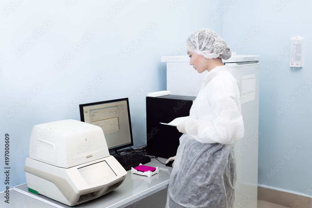 Female genetics worker placing the strips with DNA into the PCR thermal ...