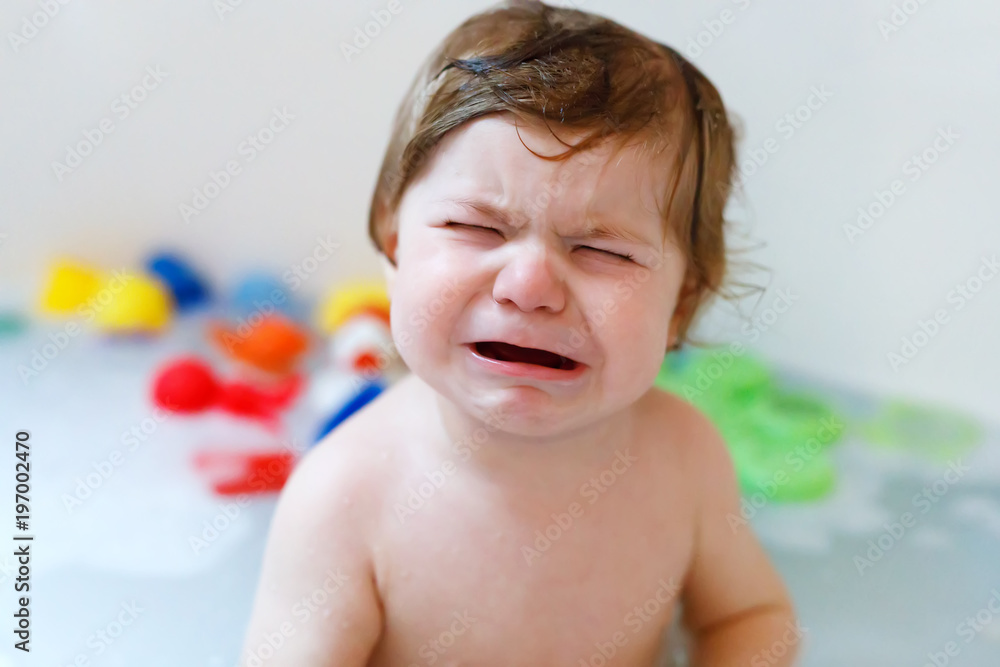 Cute adorable sad baby girl taking foamy bath in bathtub. Crying ...