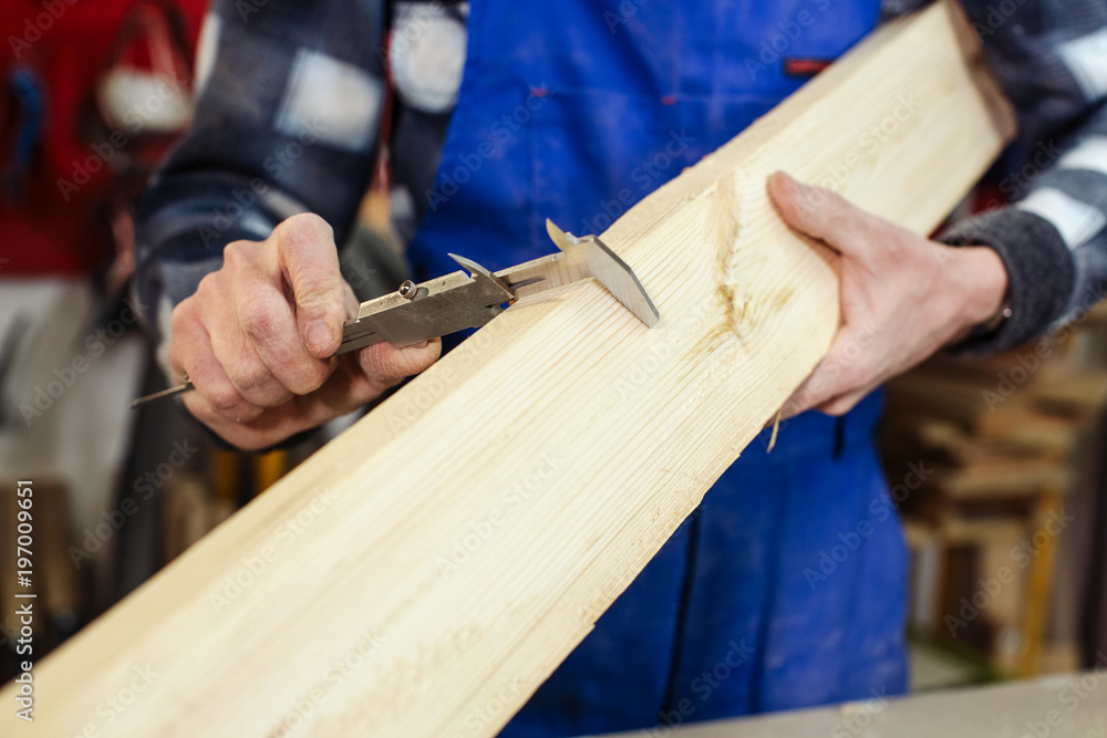 measurement of the thickness of a timber bar on a workbench by a ...