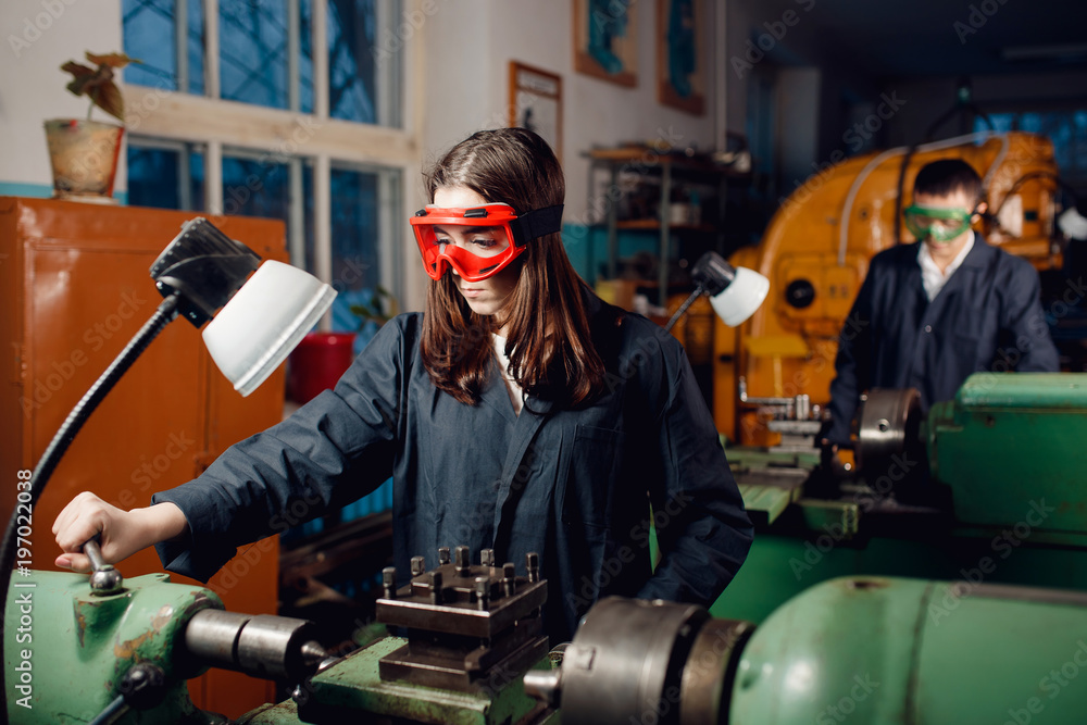 Group of working young woman and male turner engineers are standing ...