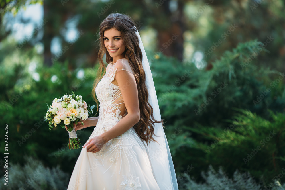 Cute young bride with long hairs holding her wedding bouquet includes ...