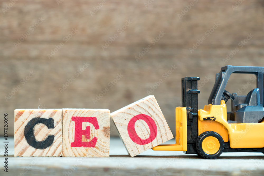 Yellow toy forklift hold letter block O to complete word CEO ...