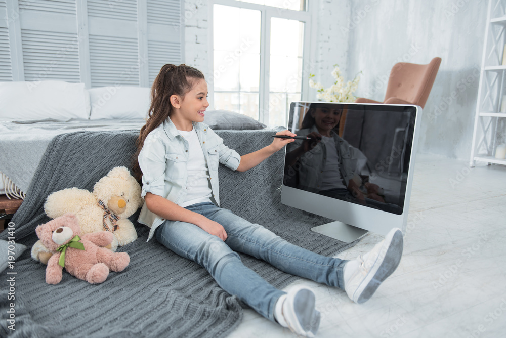 Sensory monitor. Positive cute nice girl sitting on the floor and ...