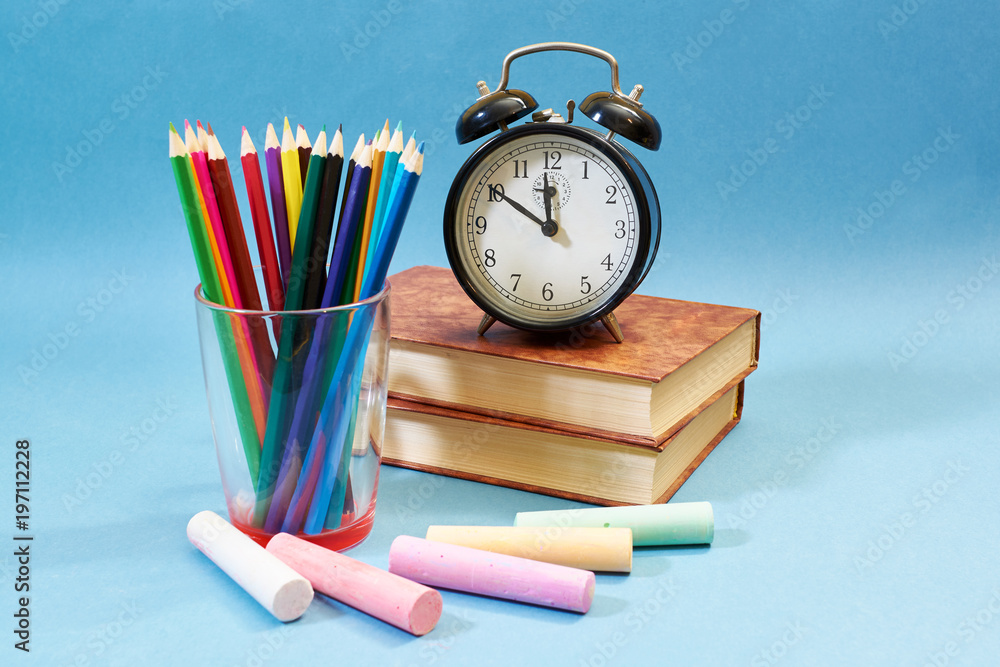 background with books, alarm clock, pencils and chalks on blue ...