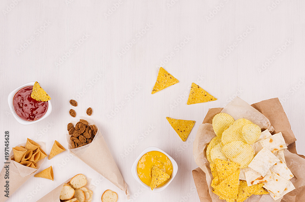 Golden different snacks on craft paper cone, triangles nachos, sauce in ...