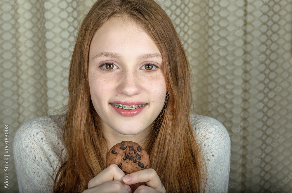 girl teenager with long red hair braces on her teeth, holds oatmeal ...