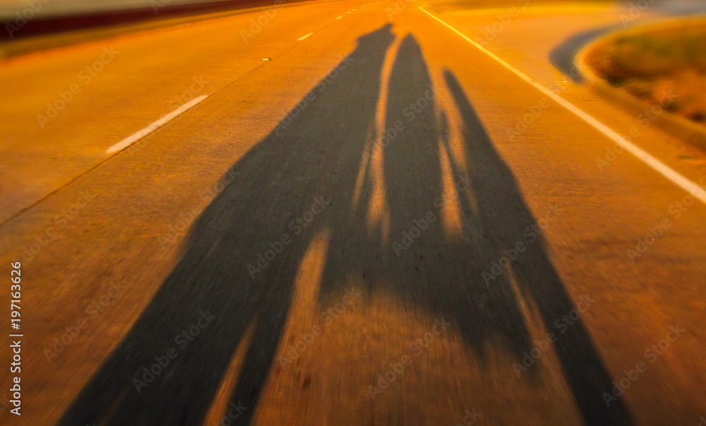 Long shadow of a three-wheel motorcycle on the asphalt road at sunset ...