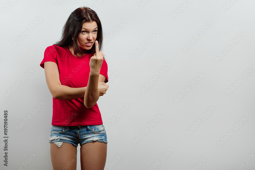 Young, beautiful girl showing the middle finger. Isolated on a light ...