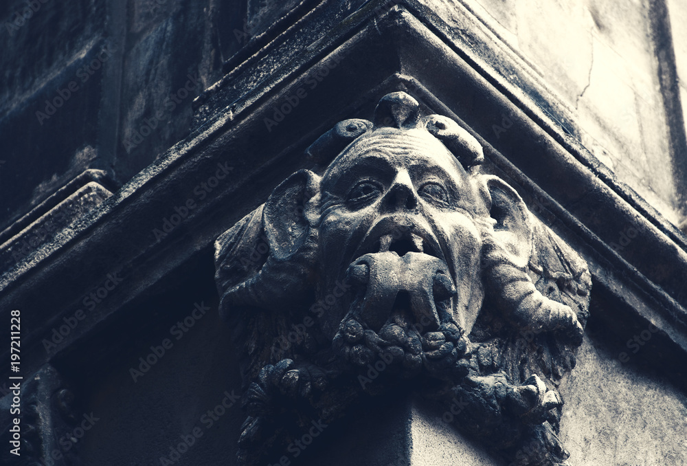 Gargoyle with protruding tongue. Architectural detail of old house in ...