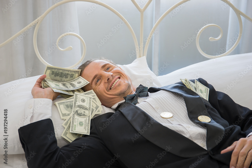 Rich man lying on the bed with dollar banknotes. Success business ...