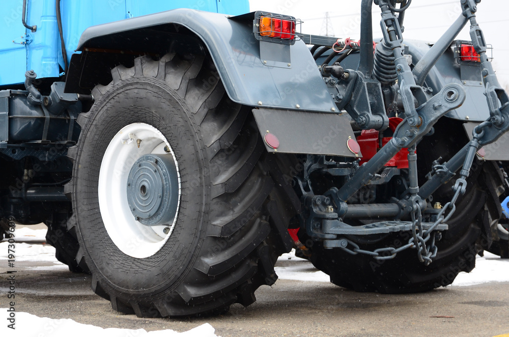 Wheels of back view of new tractor in snowy weather. Agricultural ...