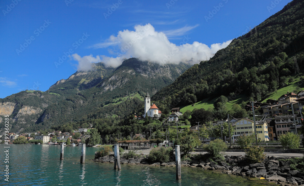 A church by Lake Lucerne with beautiful mountains and the emerald water ...