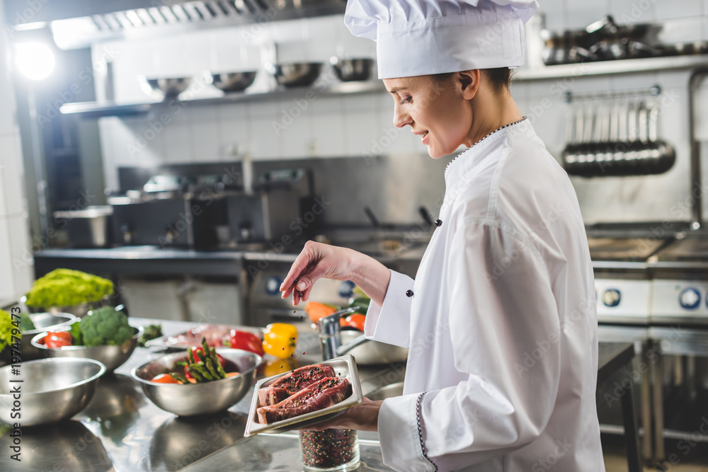 attractive chef adding herbs to raw steaks at restaurant kitchen Stock ...
