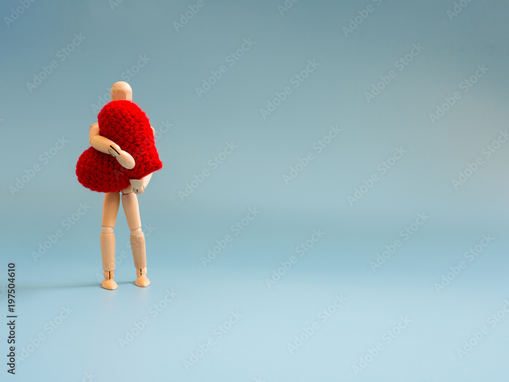 Wooden puppet standing and holding a red heart on the blue screen ...