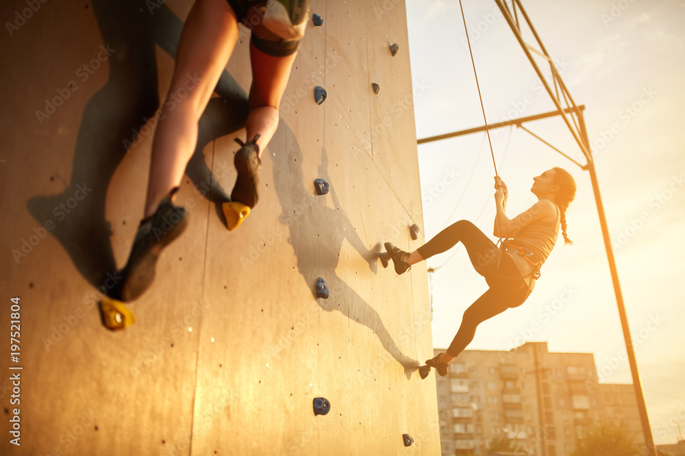 Bottom view of two young climbers practice on artificial climbing wall ...