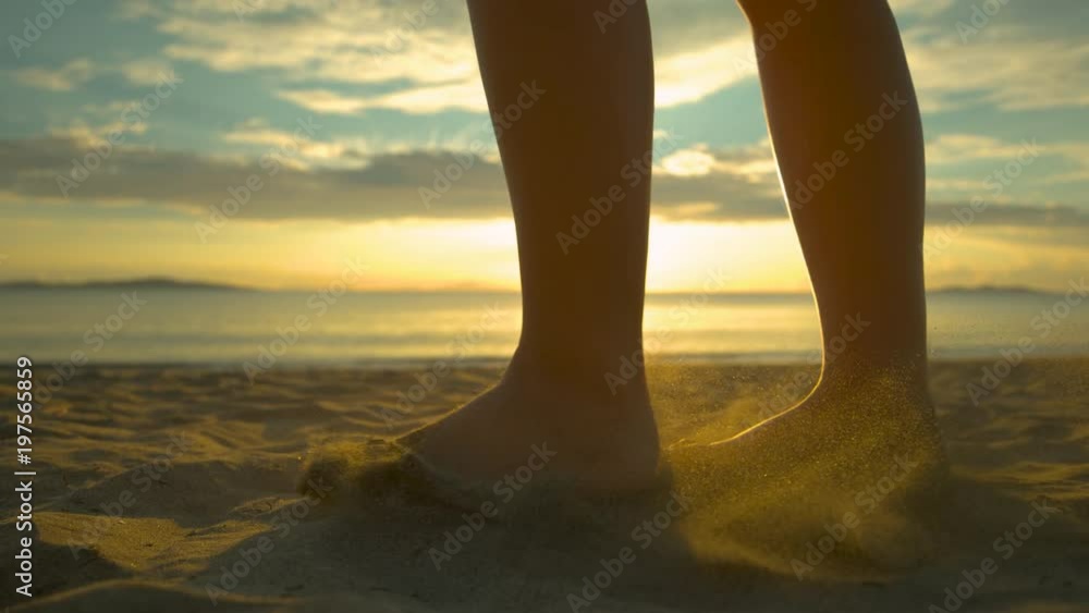 SLOW MOTION, CLOSE UP, LENS FLARE: Female kicking sand sends sparkling ...