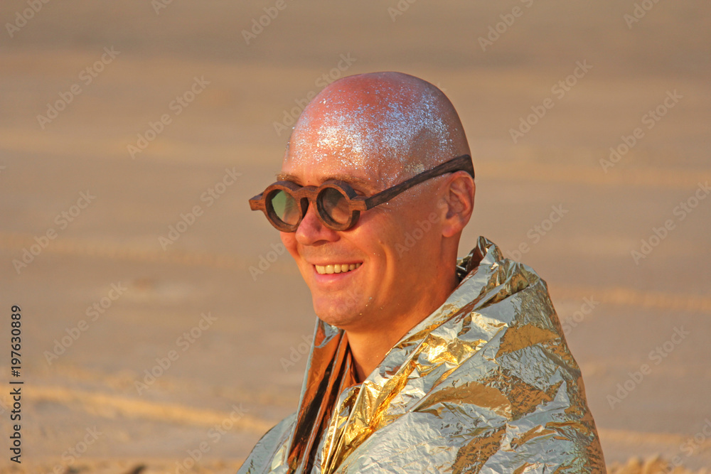 A bald and handsome man freak smiles in a golden cape or clothes and ...