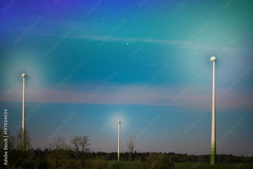 Abstract shot of wind turbines in the meadow on starry night sky ...
