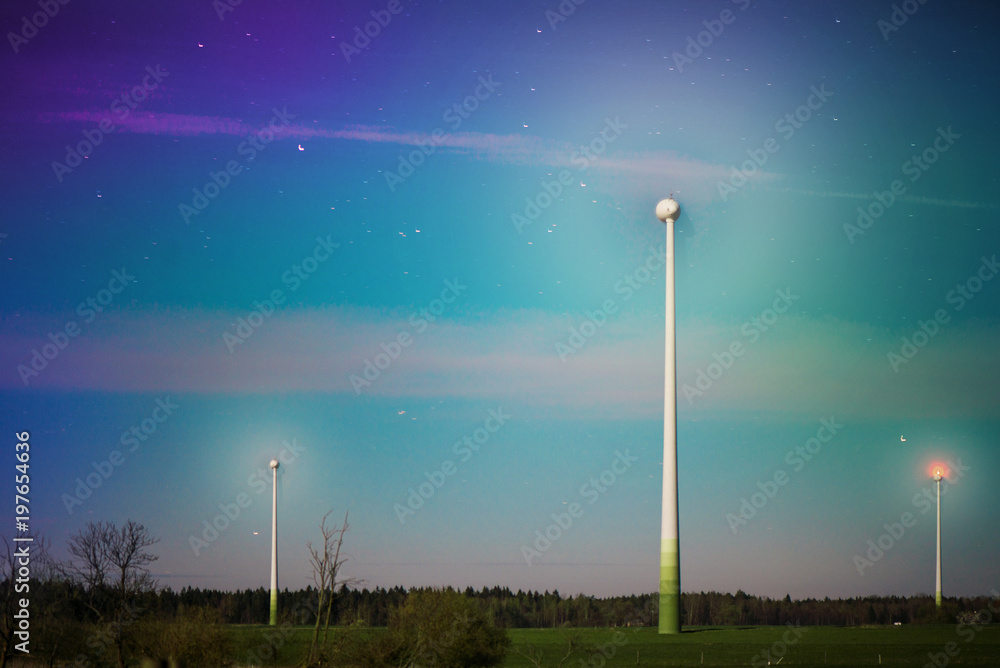 Abstract shot of wind turbines in the meadow on starry night sky ...