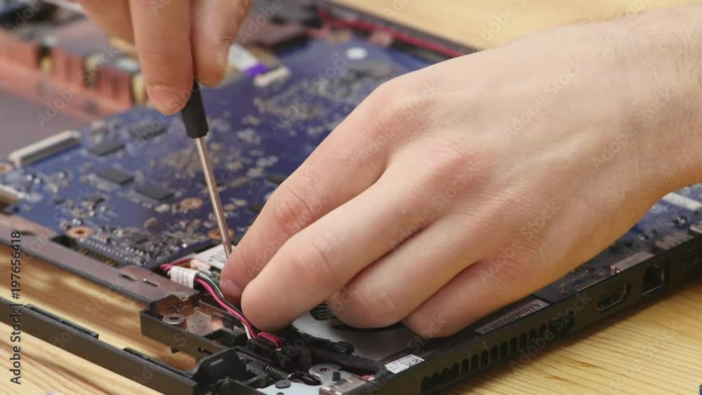 Laptop disassembling in repair shop, close-up. Disassembled computer motherboard on repairman ...